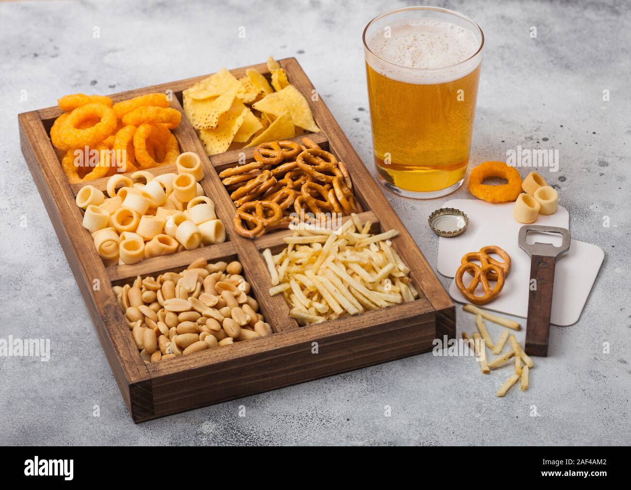 Glass of craft lager beer and opener with box of snacks on light ...