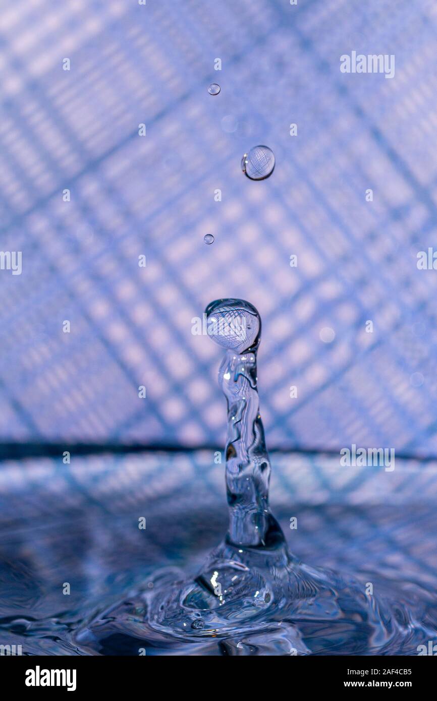 water drops splashing in front of a blue striped background with ...