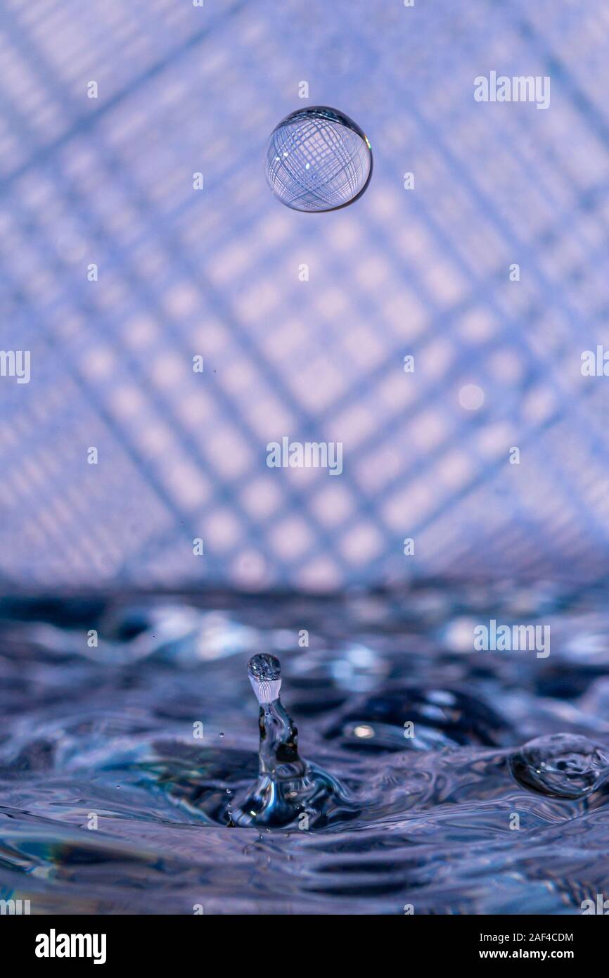 water drops splashing in front of a blue striped background with ...