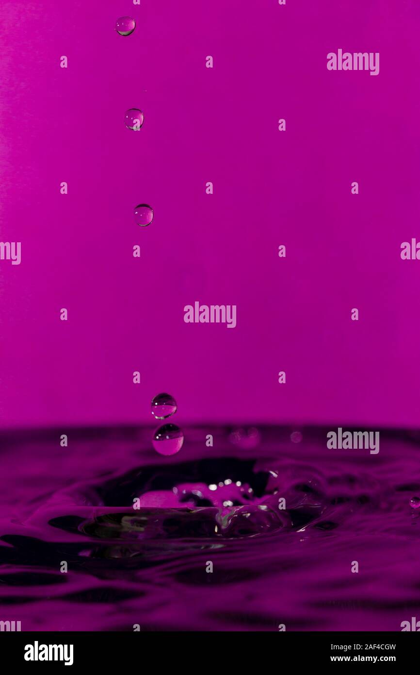 water drop splash in a purple colored glass Stock Photo - Alamy