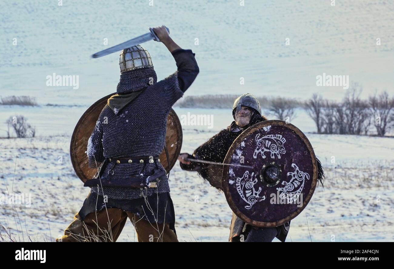 Two viking are fighting with axes and shields on the winter meadow ...