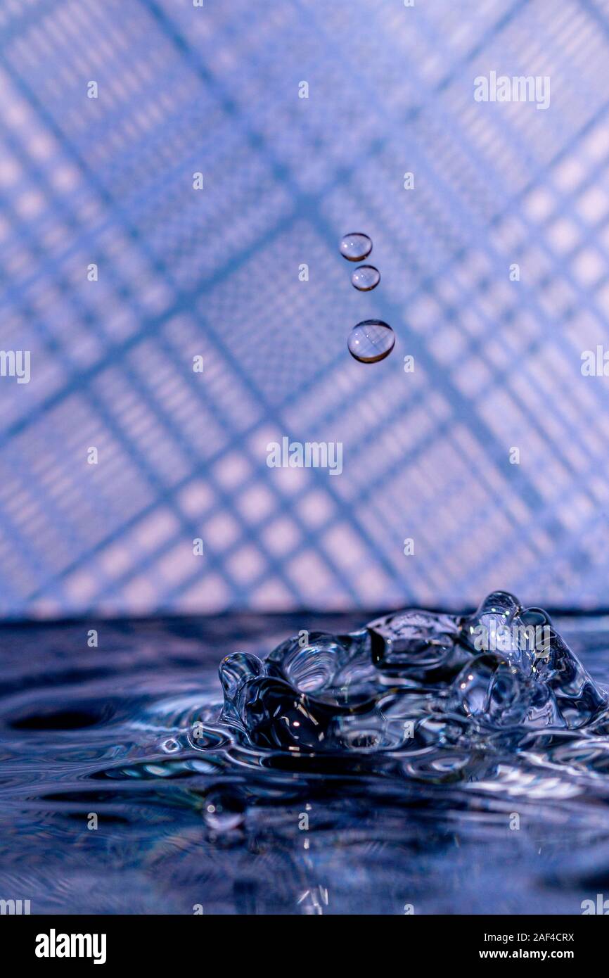 water drops splashing in front of a blue striped background with ...