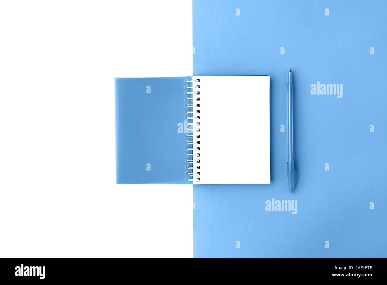 Top view of opened trendy blue cover spiral notepad with pen on blue ...