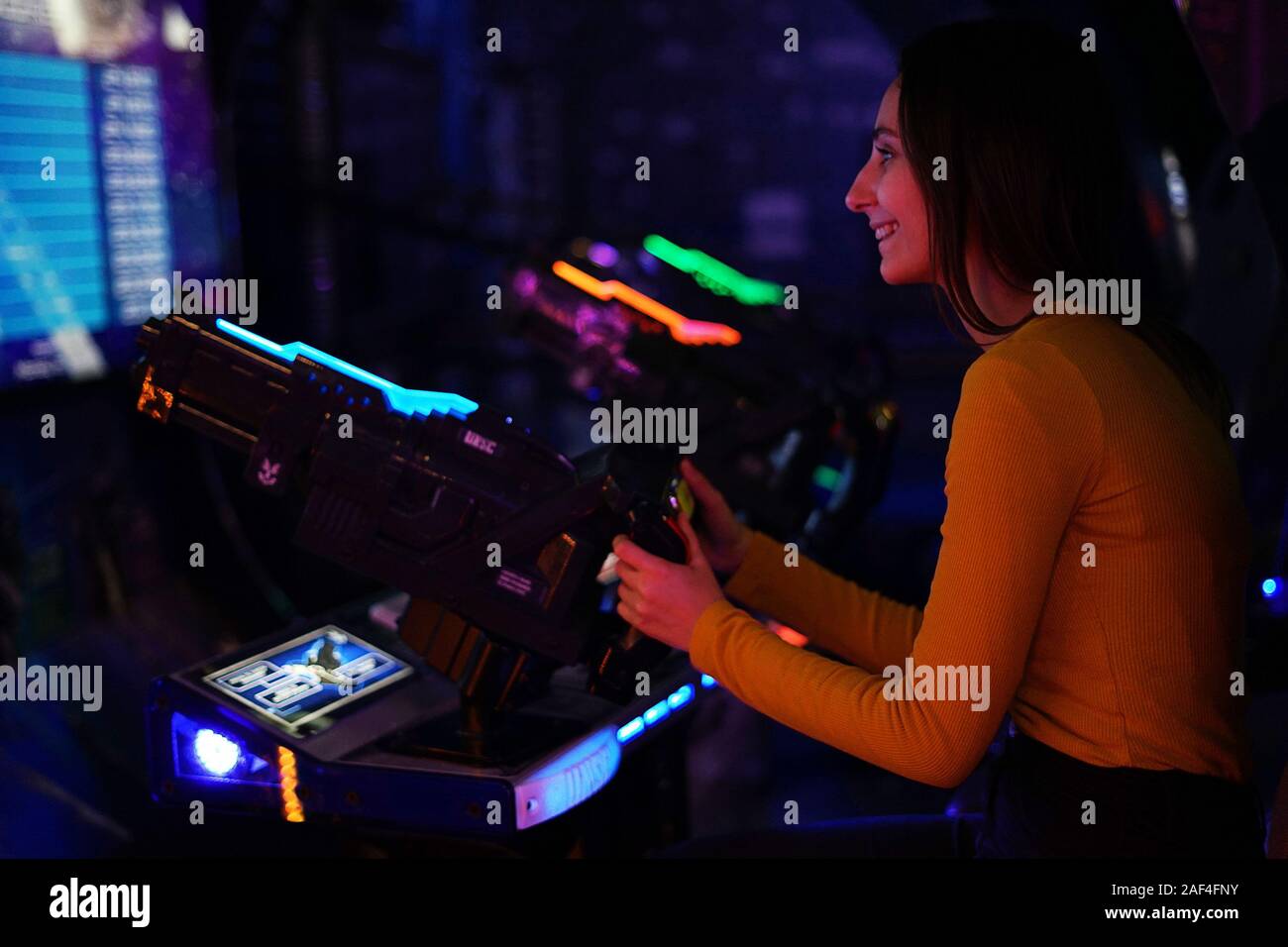 Beautiful young woman dressed in yellow playing in a playmachine in an ...