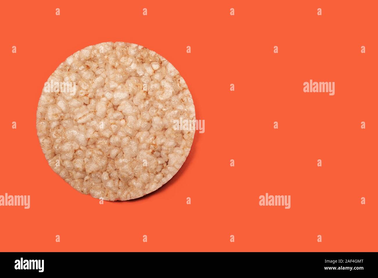 one rice or corn biscuits on an orange-carrot color background, top ...