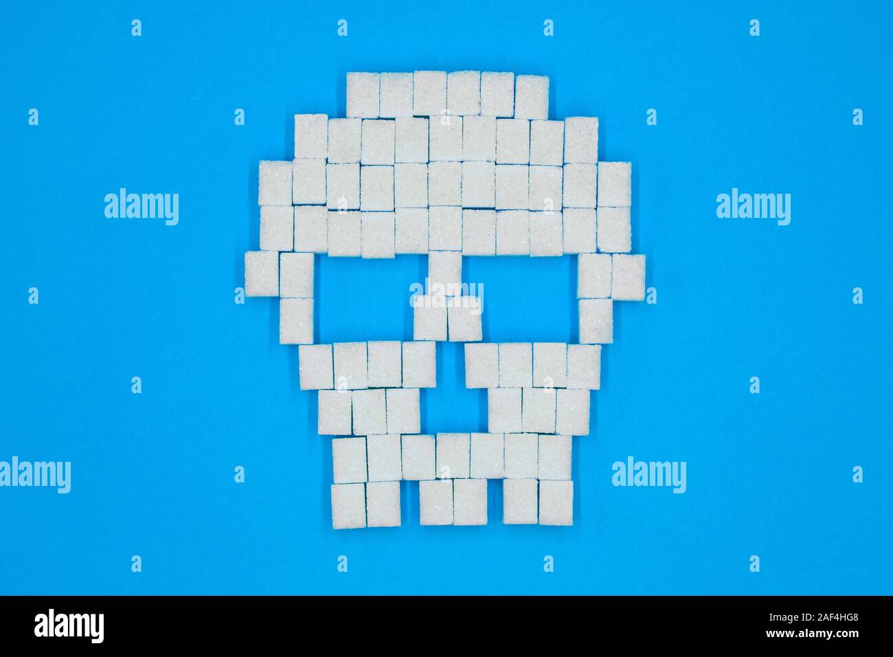 Sugar cubes laid out in shape of skull. Concept that sugar and sweets ...