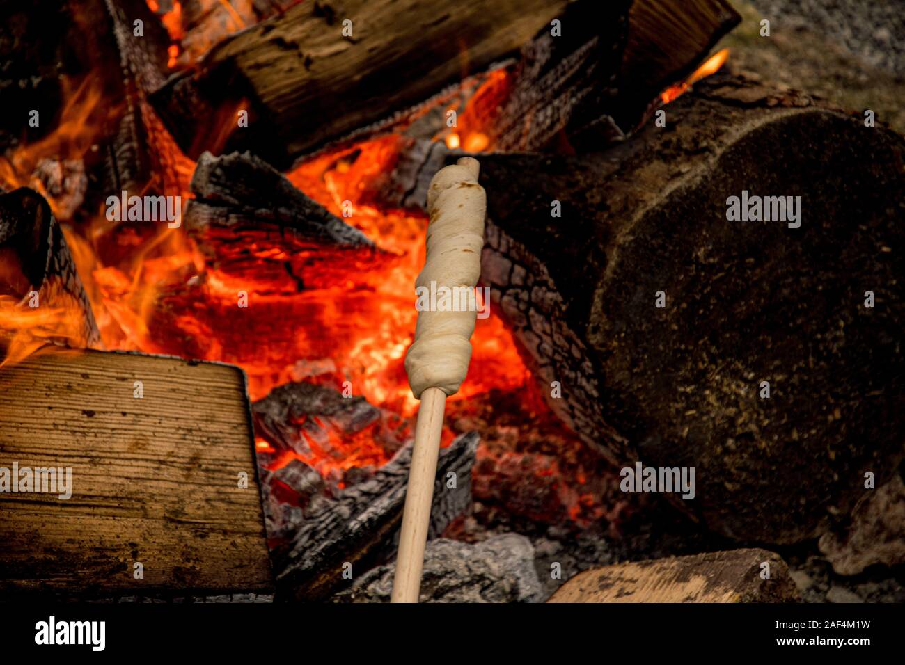 Preparing stick bread in the embers of a campfire Stock Photo - Alamy