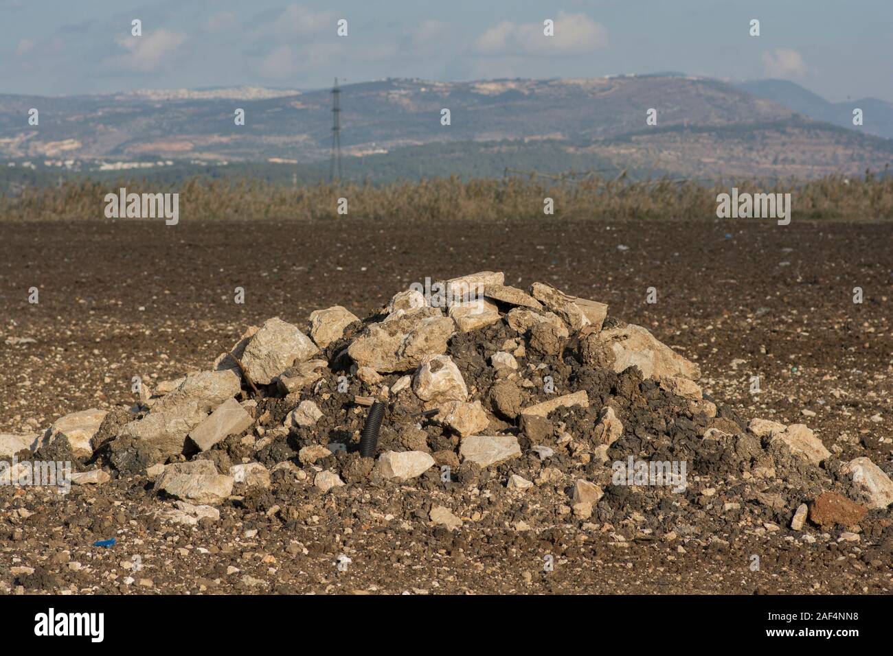 Little pile of rocks and soil, in the middle of a field, mountains in ...