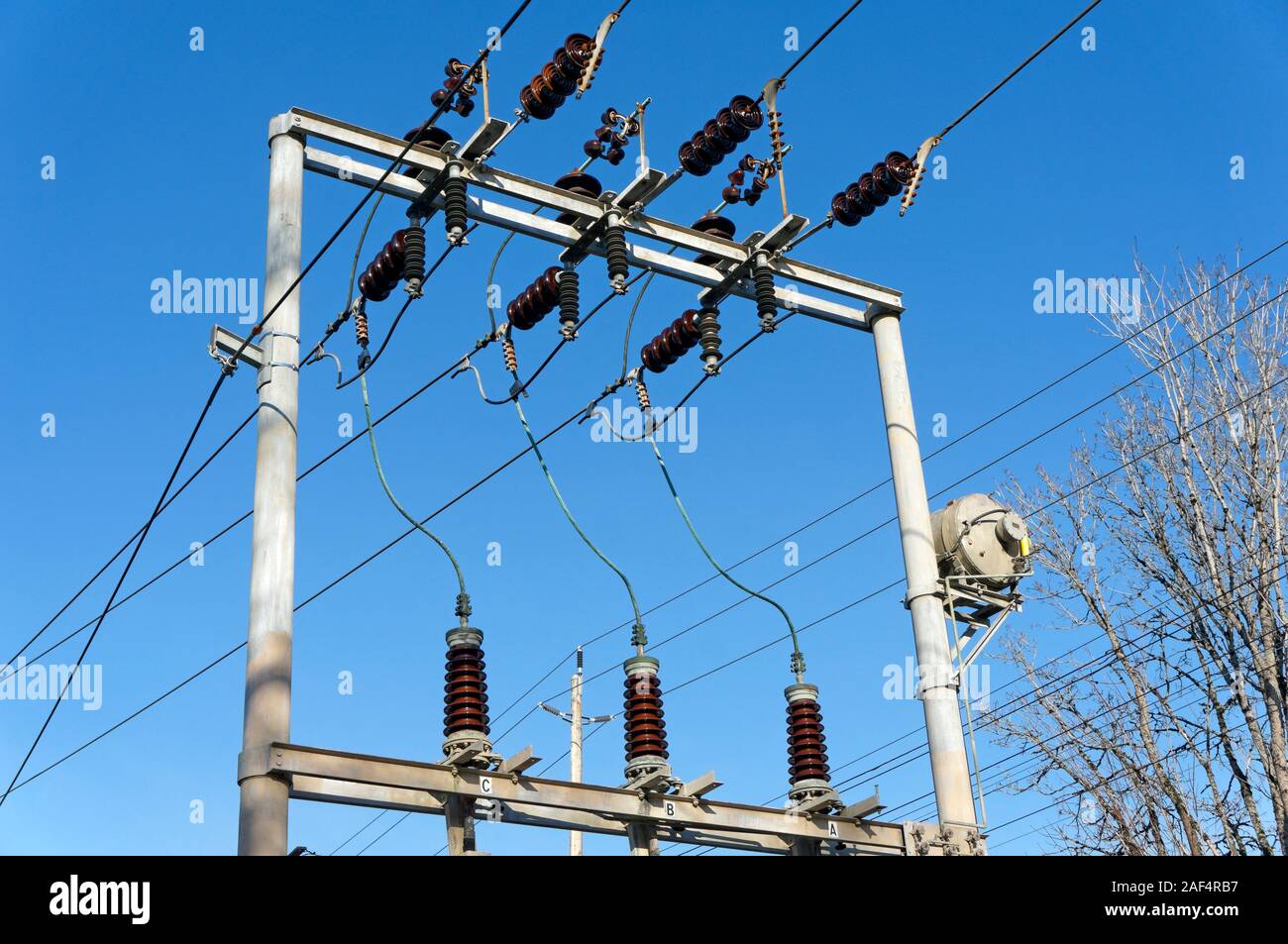 Closeup of high voltage overheard electrical power lines and insulators ...