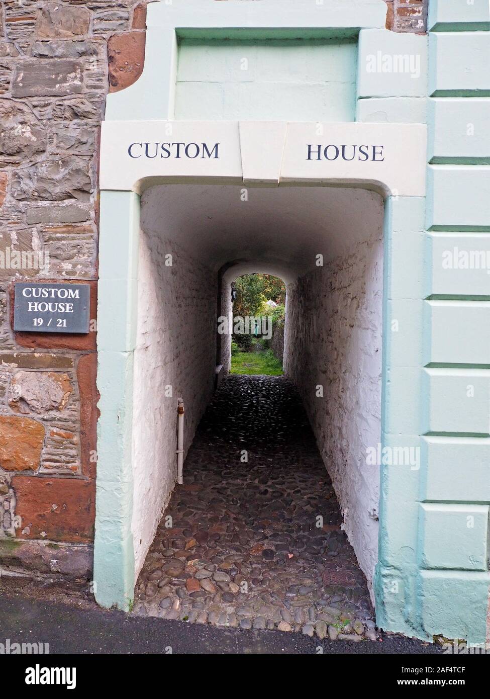 cobbled white-painted alleyway from street with sign Custom House above ...