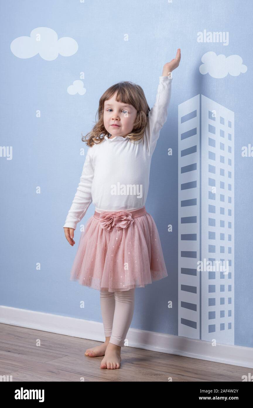 Girl rising her hand to show how tall she is. Concept about city, goals ...