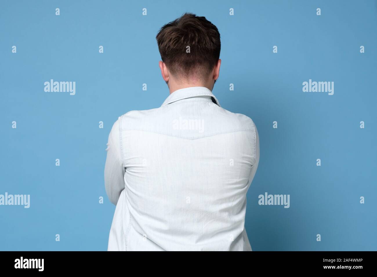 Caucasian young man standing alone isolated from rear view. Studio shot ...