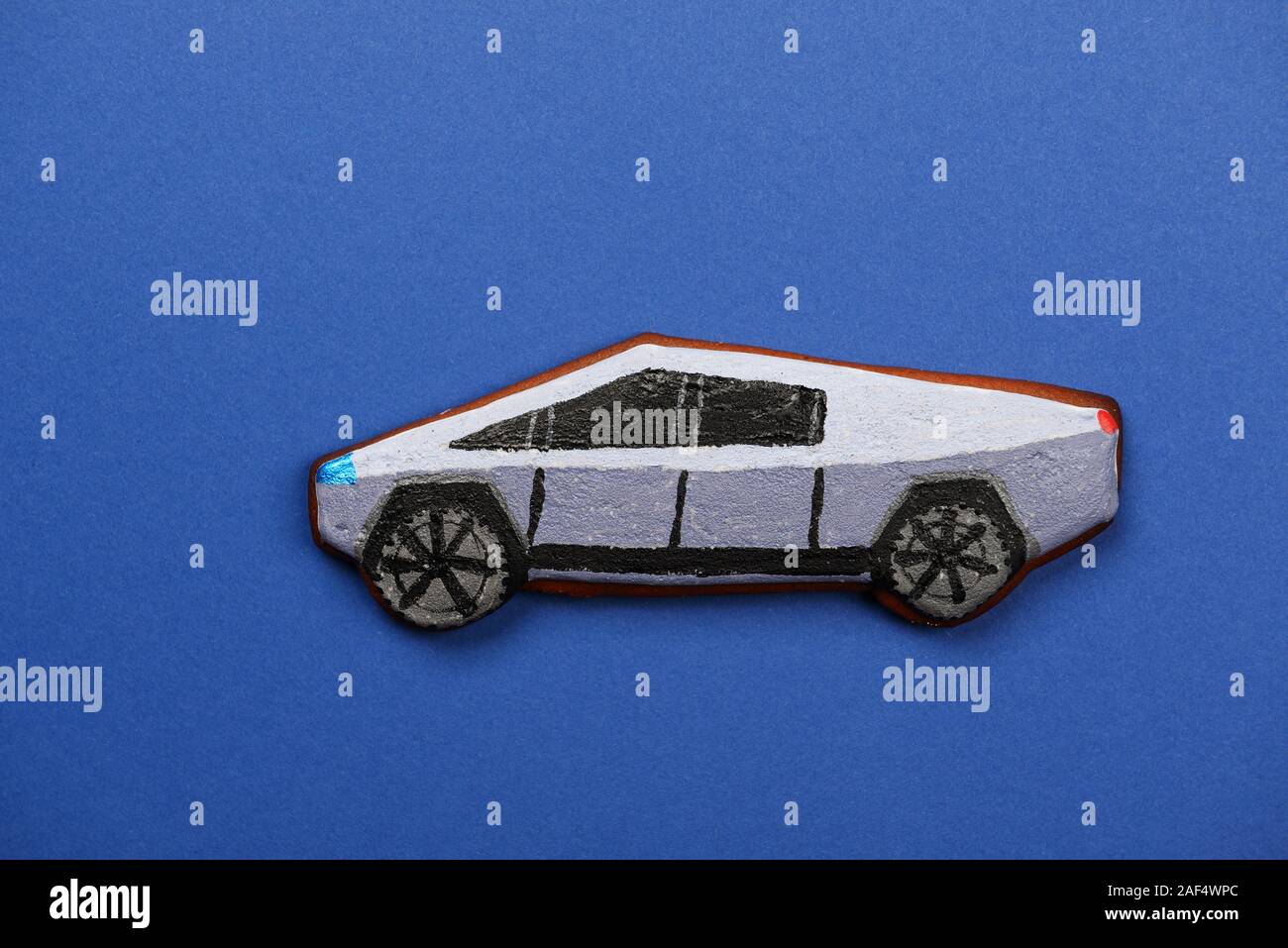 The hand-made eatable gingerbread Tesla Cybertruck electric car on blue ...
