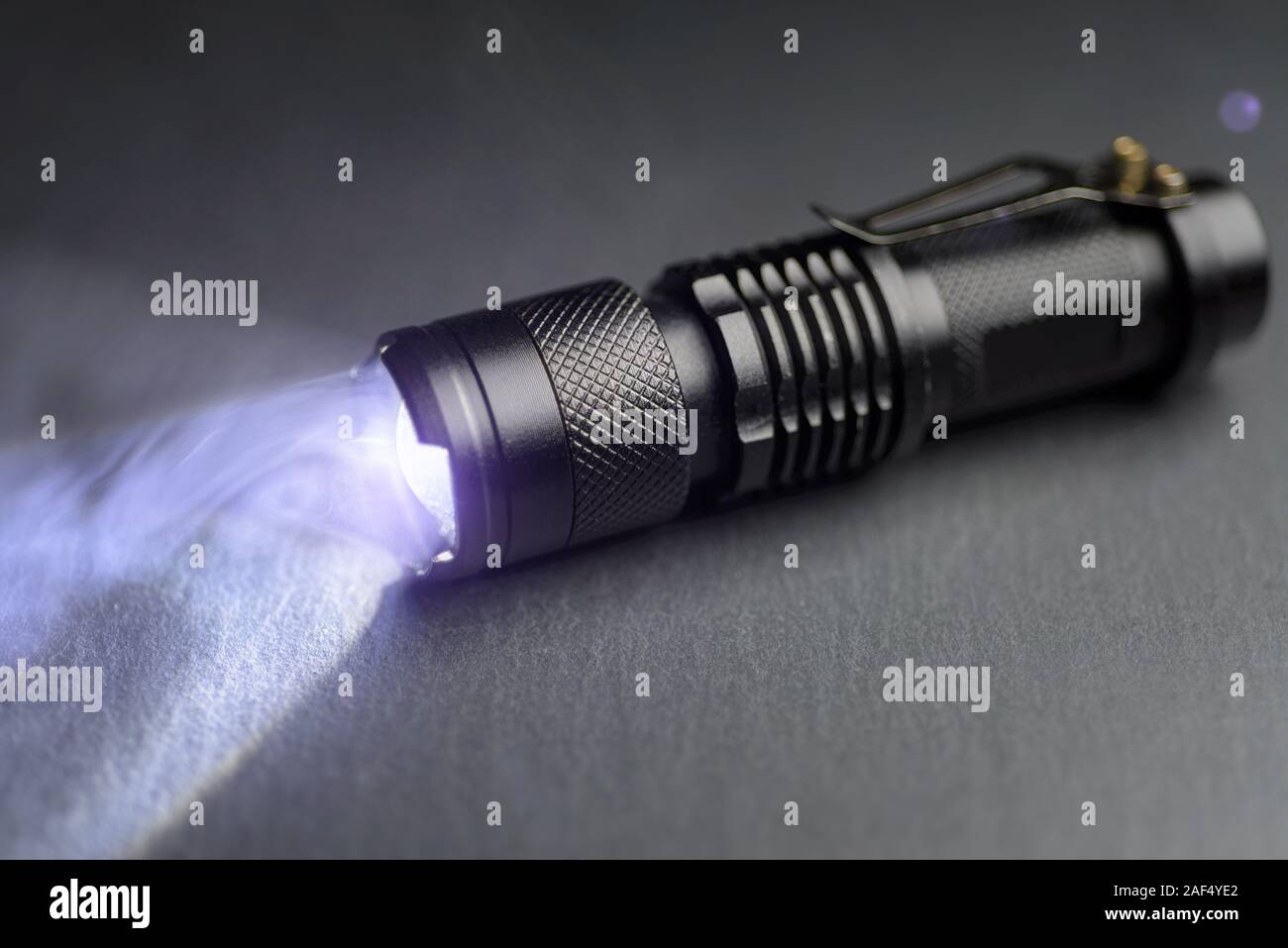 Tactical waterproof flashlight. LED flashlight shines on the table in ...