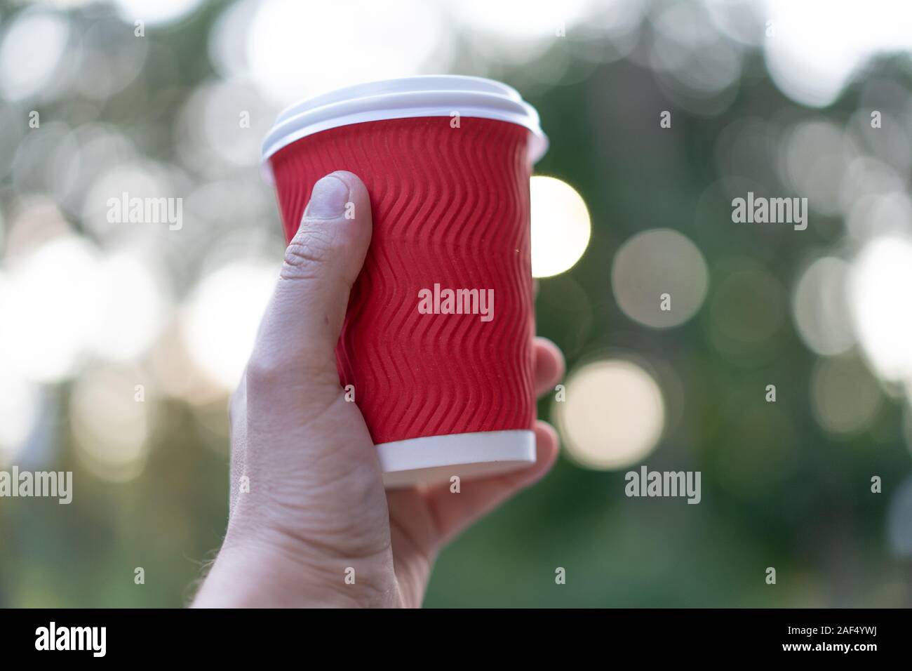 Red paper cup for drinks in hand on a background of nature. Cup coffee ...