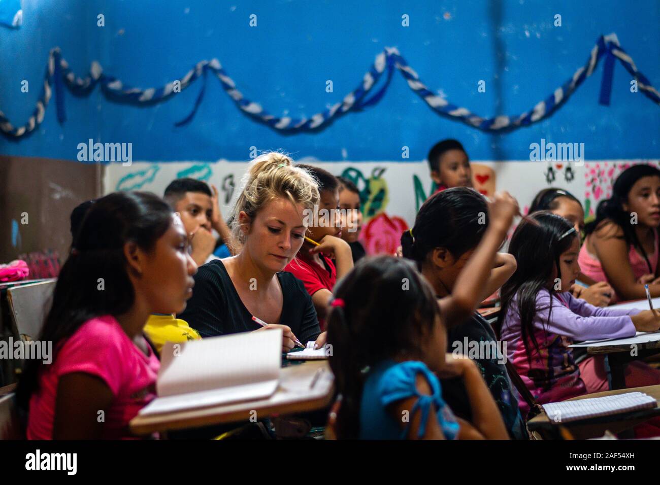 caucasian Woman helping teach english to hispanic children in ...