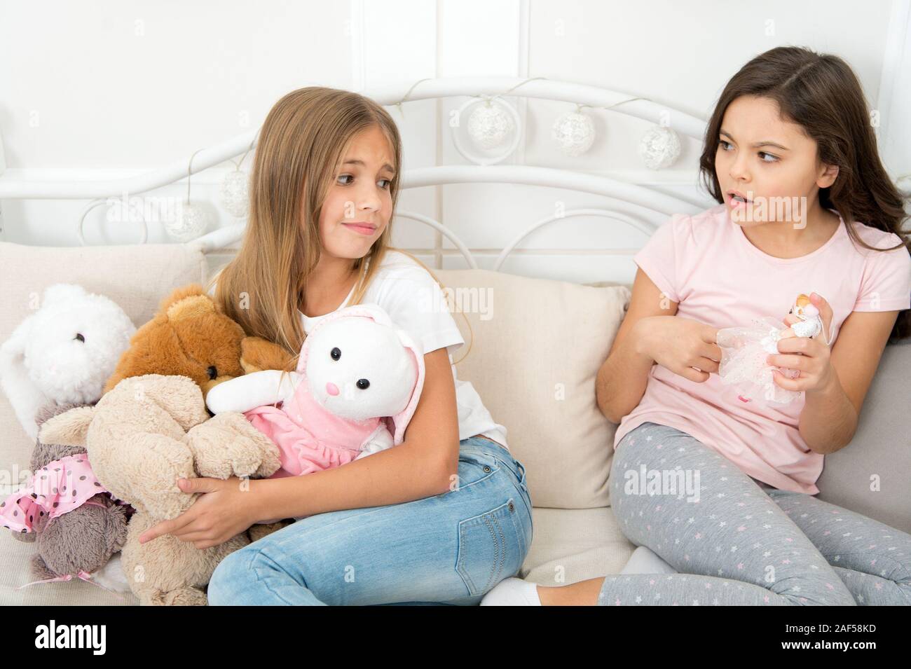 Kids play toys in bed. Little girls spend time together. Teach sister ...