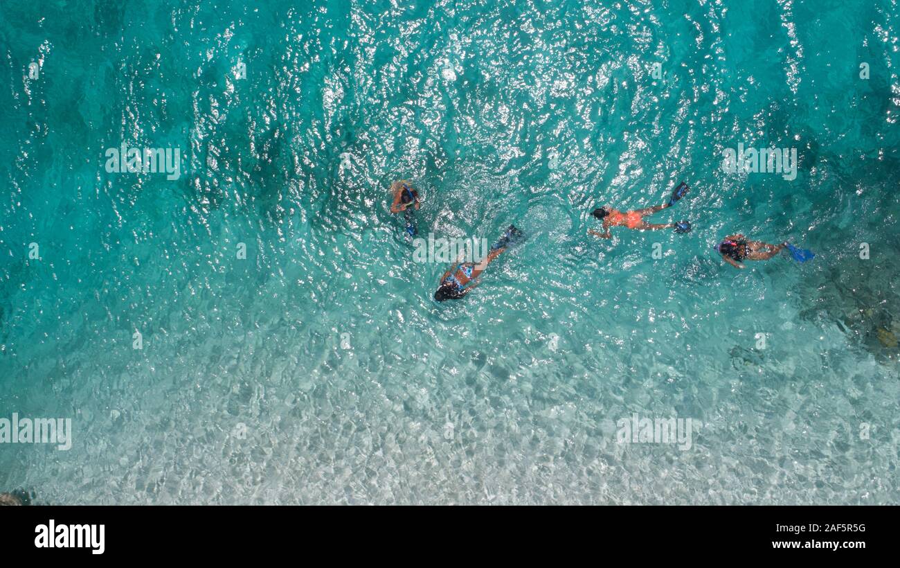Young girls snorkeling in blue clear water above coral reef on ...