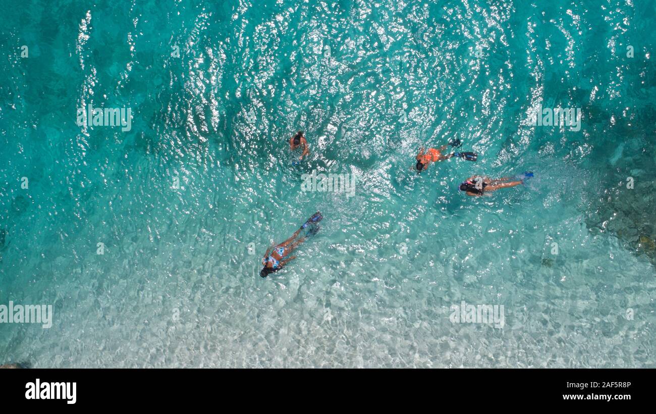Young girls snorkeling in blue clear water above coral reef on ...