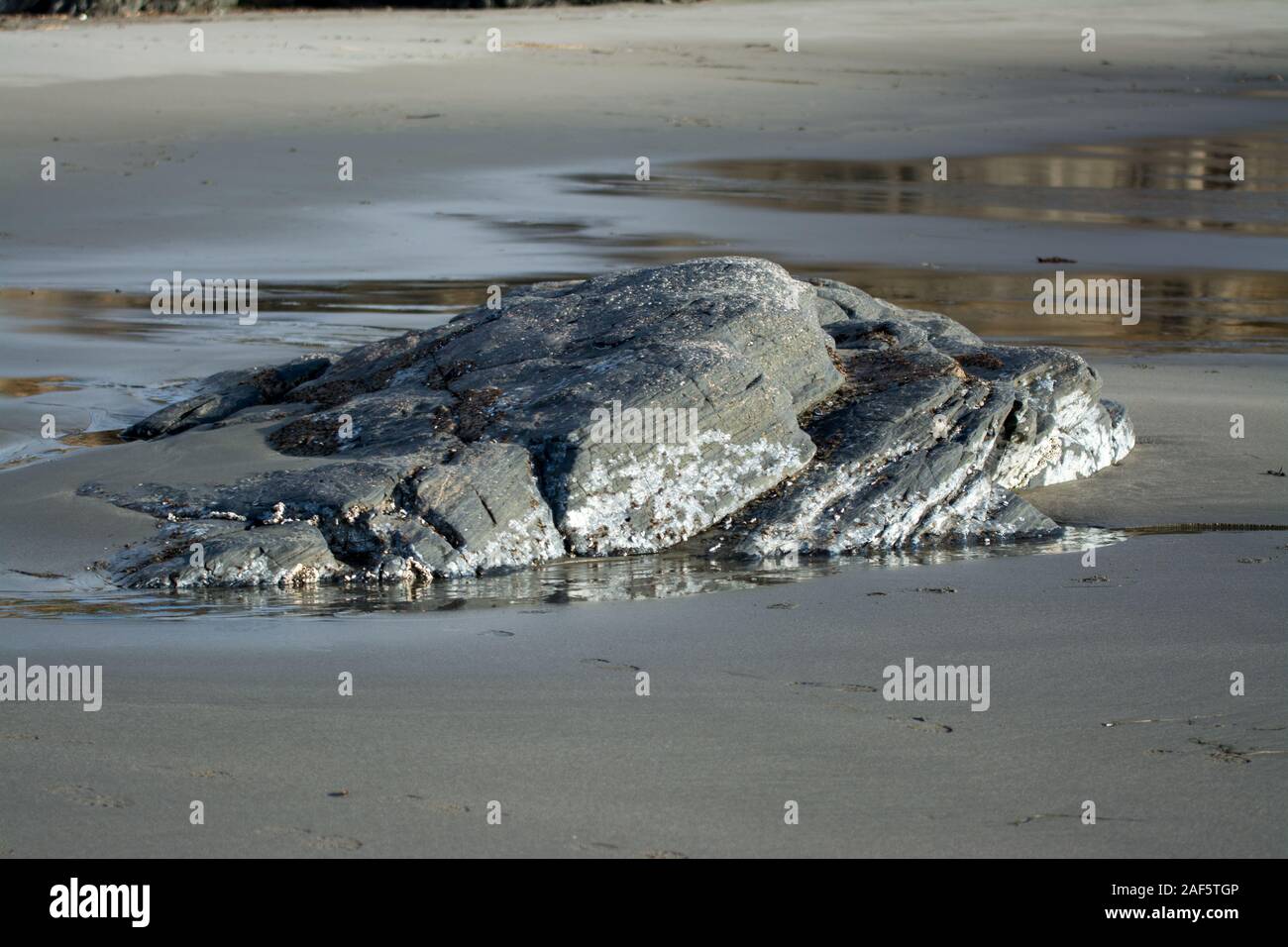 Rock boulder revealed by waves beach sand Stock Photo - Alamy
