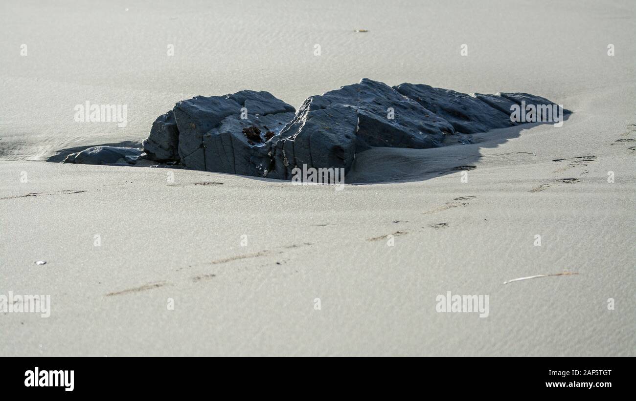 Rock boulder revealed by waves beach sand Stock Photo - Alamy