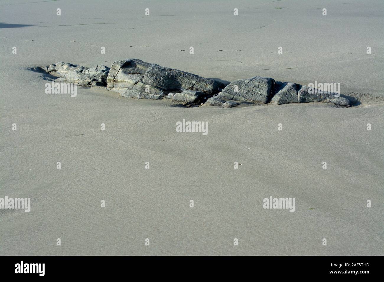 Rock boulder revealed by waves beach sand Stock Photo - Alamy