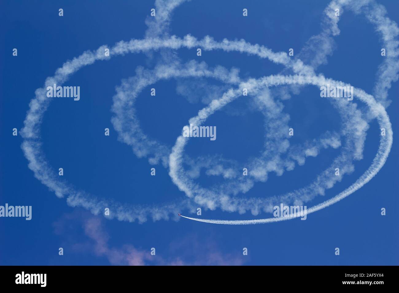 Upward blue sky view of an artistic abstract airplane skywriting design ...