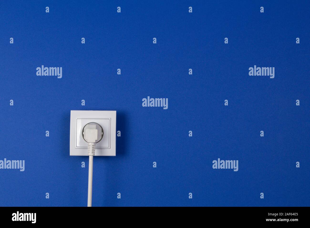 White cable plugged into electrical socket on blue navy color ...