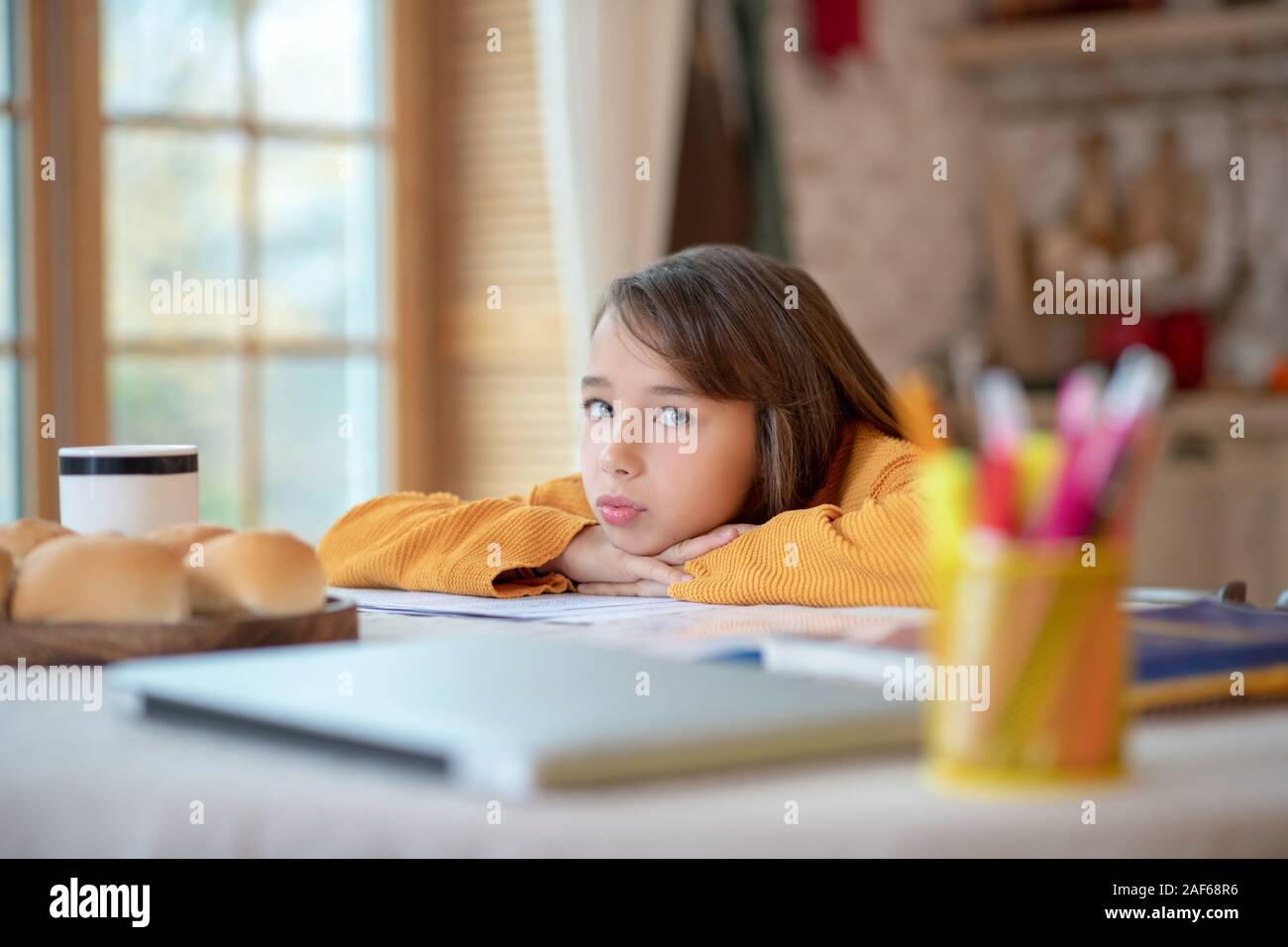 Cute girl in orange shirt looking bored Stock Photo - Alamy