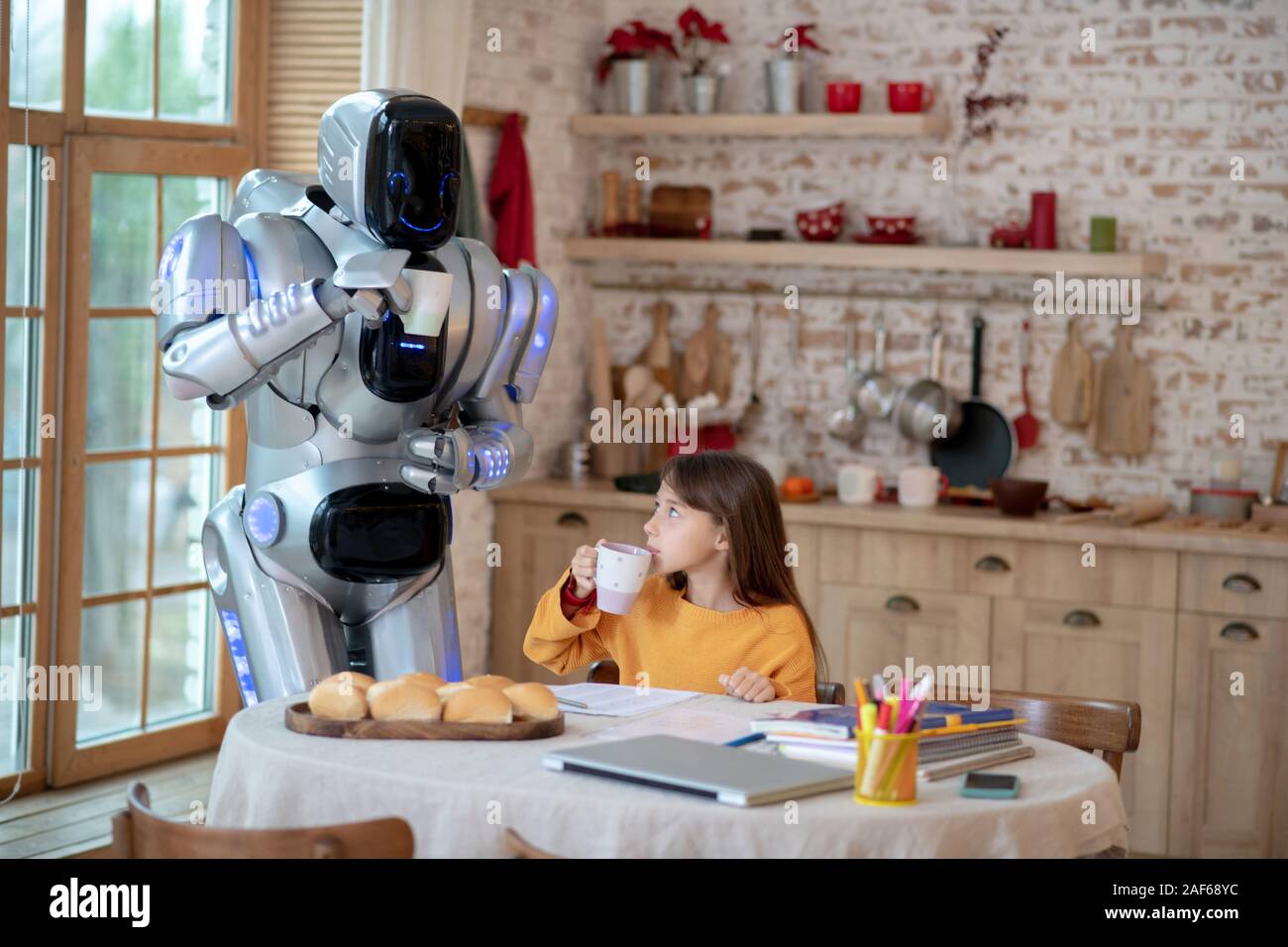 Cute girl and her house robot having tea Stock Photo - Alamy