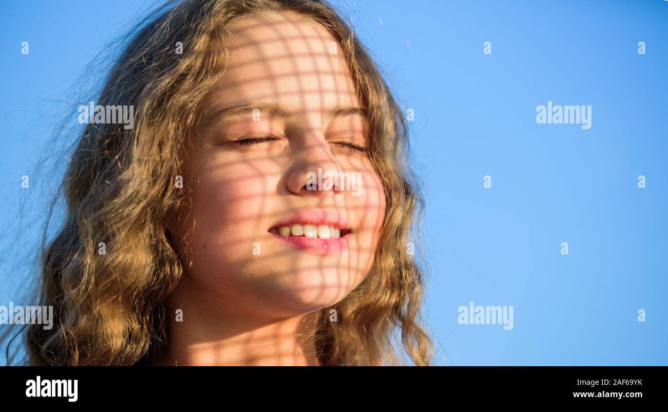 Sunscreen concept. Child pleased with warm sunlight looks relaxed blue ...