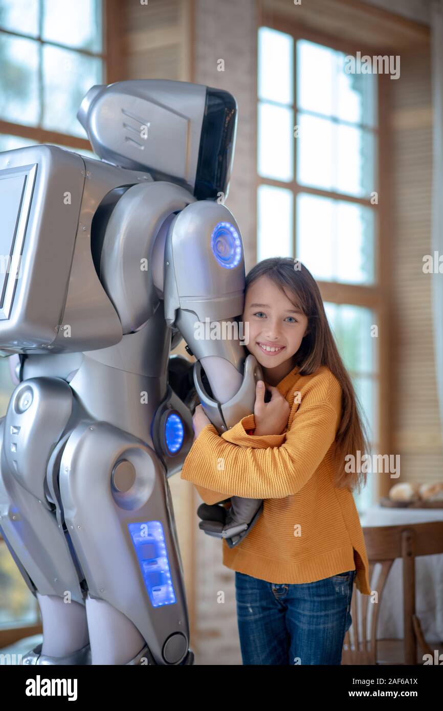 Pretty girl with long hair hugging her house robot Stock Photo - Alamy