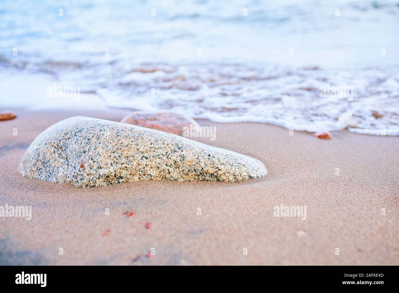 Sandy beach with waves from the sea. Rock in sand near the ocean Stock ...