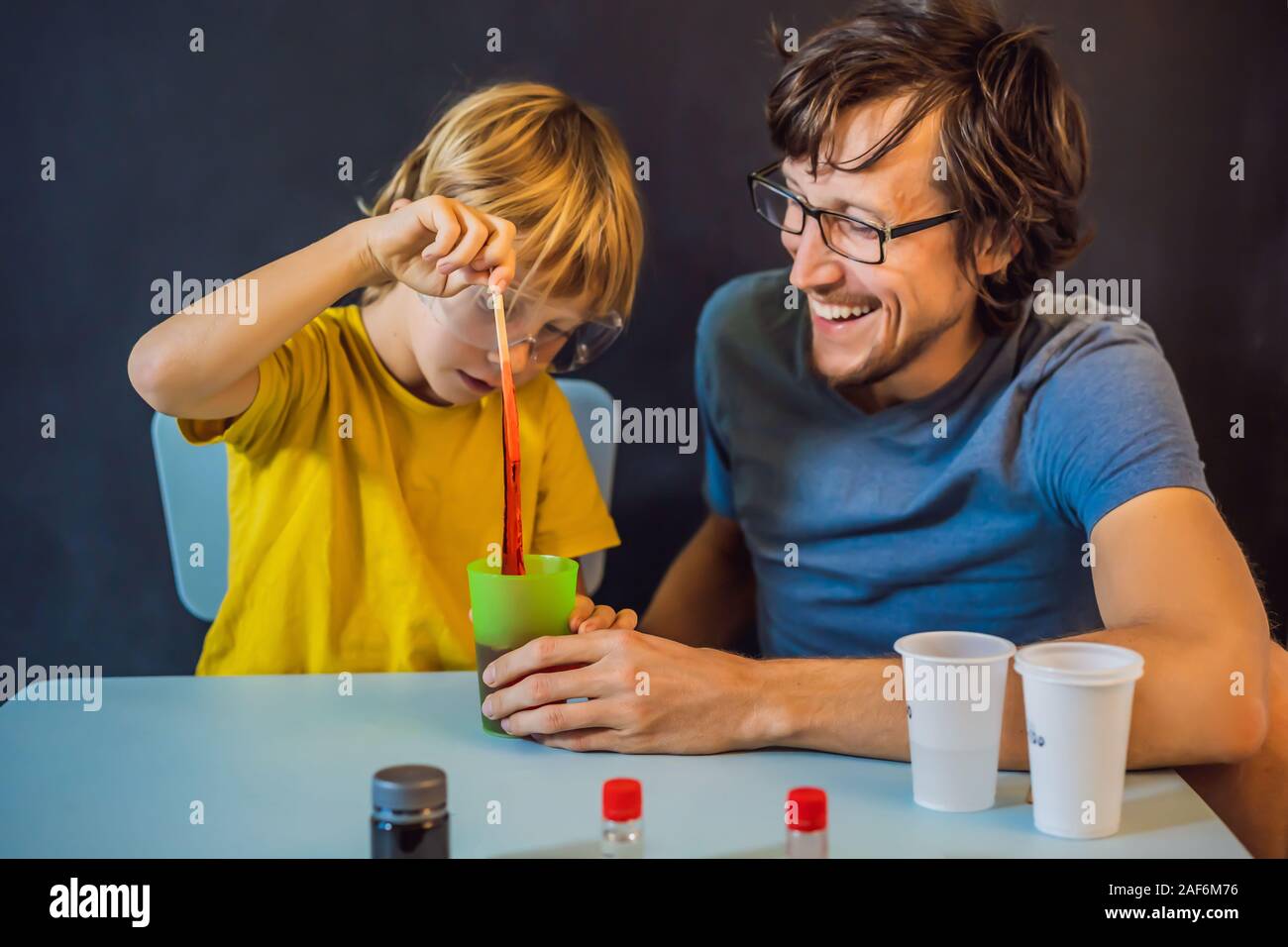 Father and son conduct chemical experiments at home. Home made slime ...