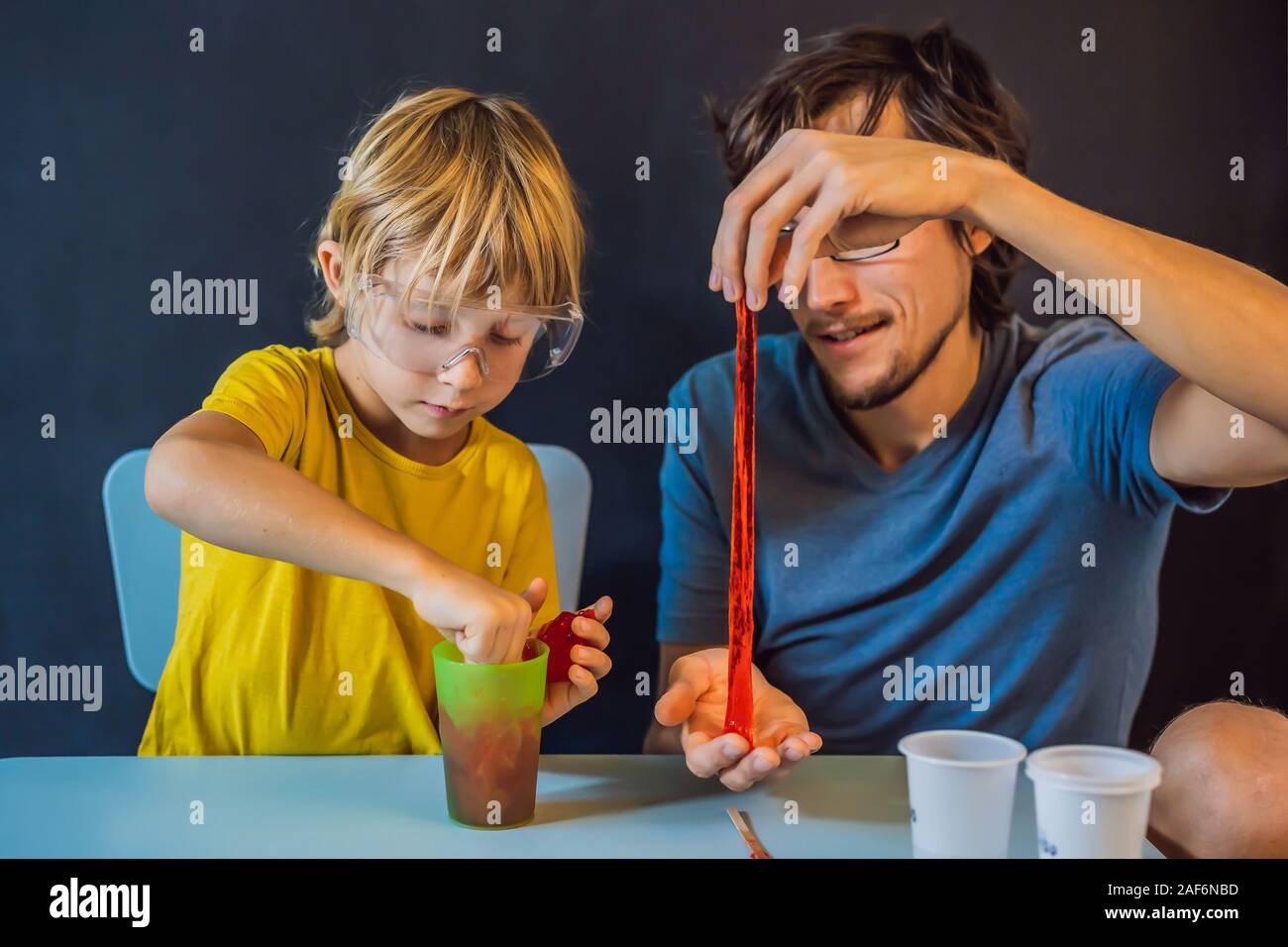 Father and son conduct chemical experiments at home. Home made slime ...