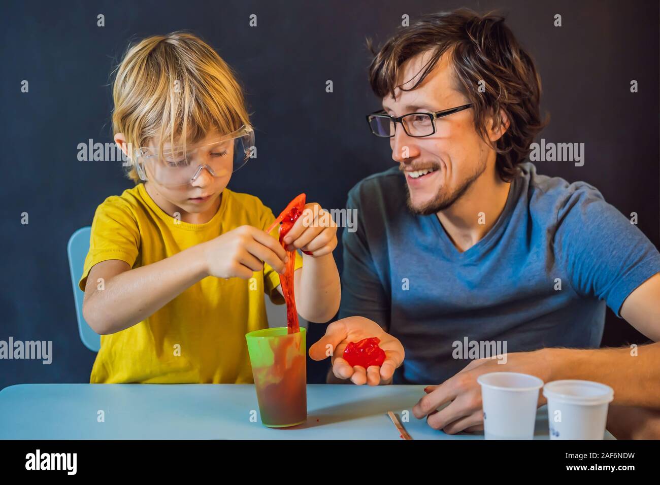 Father and son conduct chemical experiments at home. Home made slime ...