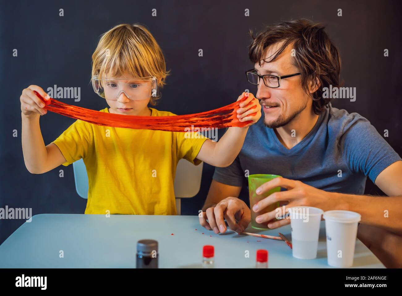 Father and son conduct chemical experiments at home. Home made slime ...
