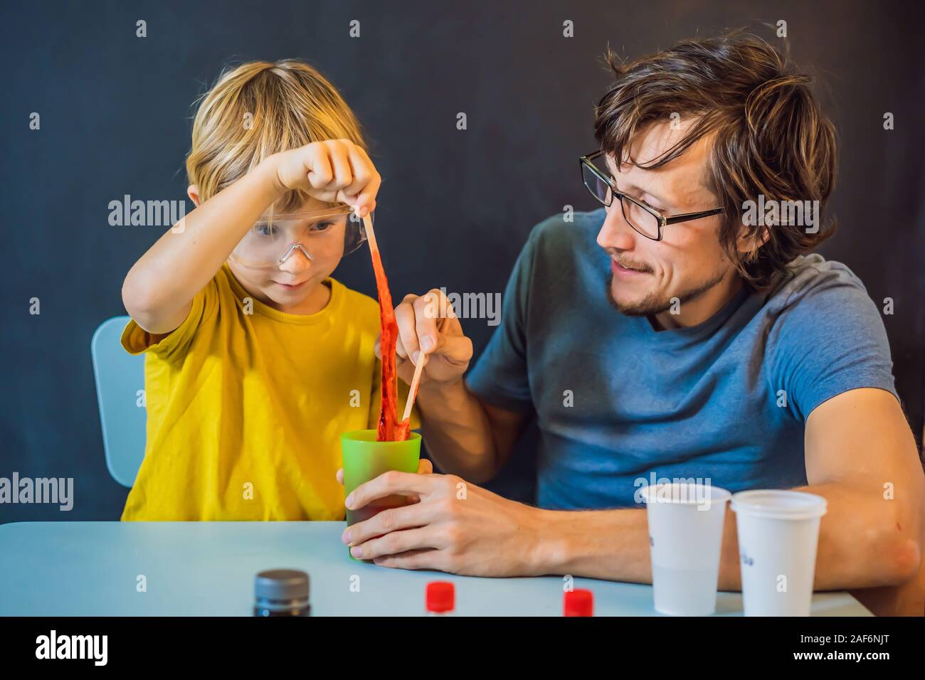 Father and son conduct chemical experiments at home. Home made slime ...