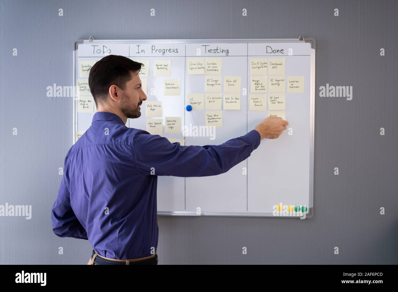 Side View Of Businessman Writing On Sticky Notes Attached To White ...