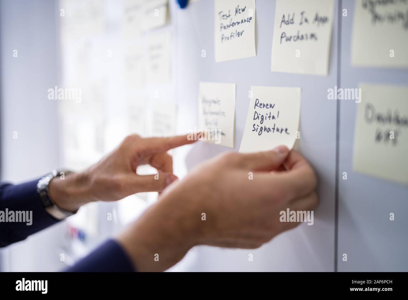 Side View Of Businessman Writing On Sticky Notes Attached To White ...