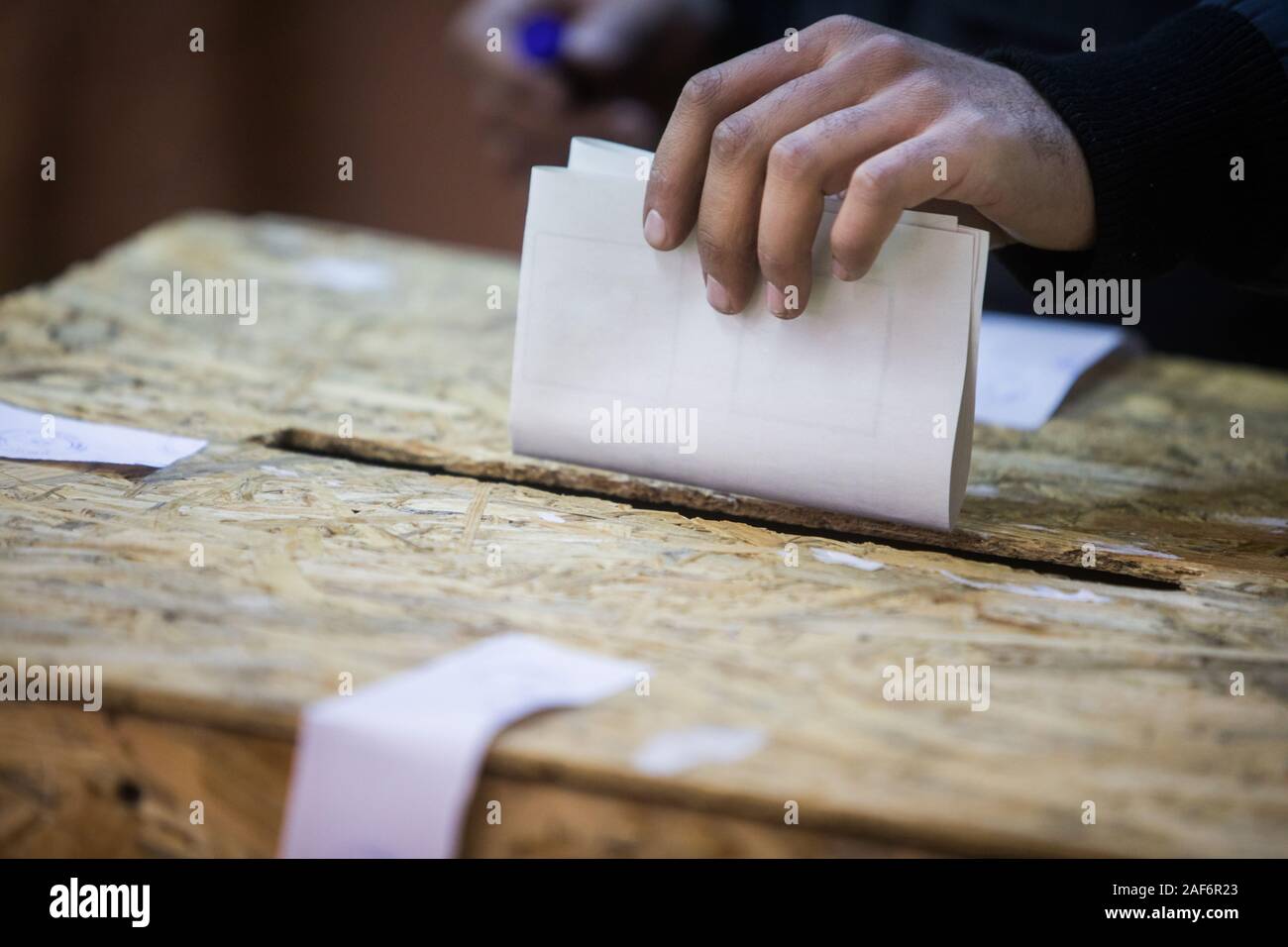 Color image of a person casting a ballot at a polling station, during ...
