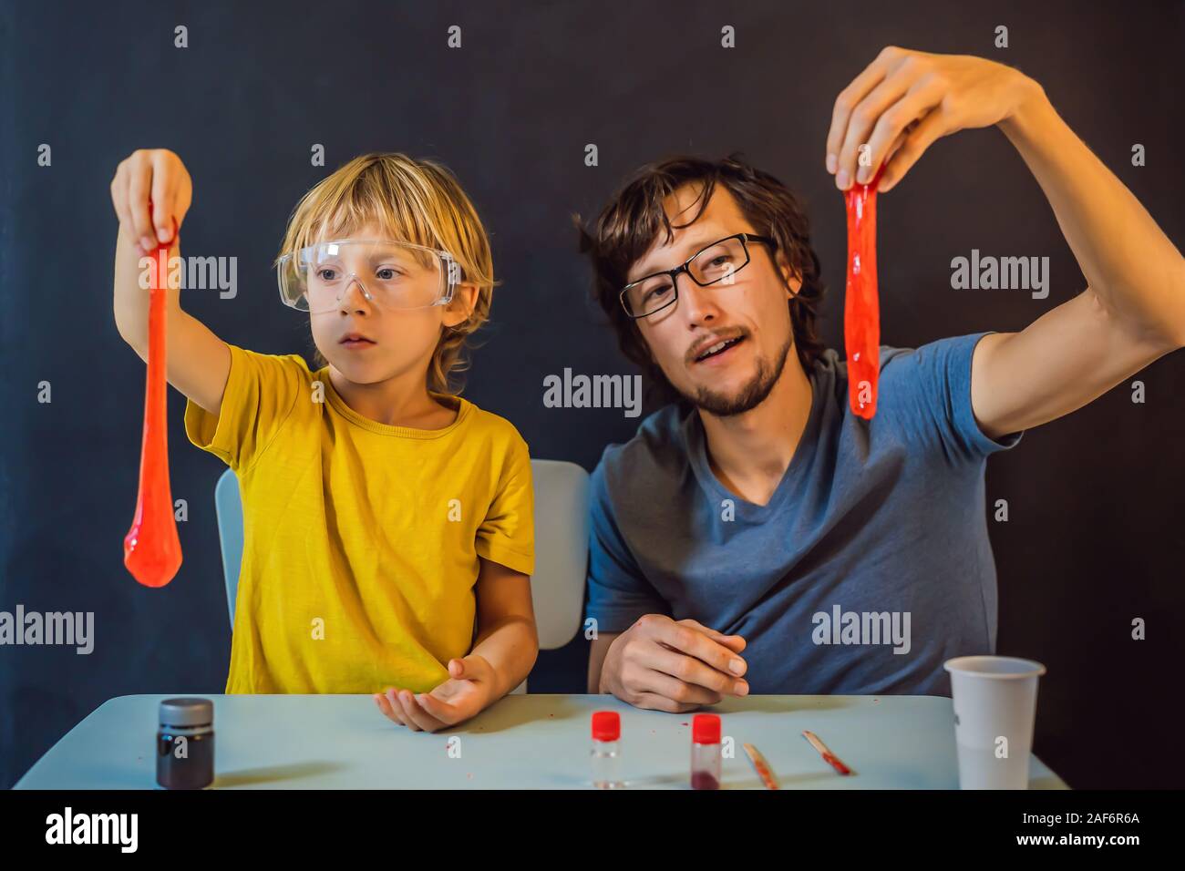 Father and son conduct chemical experiments at home. Home made slime ...