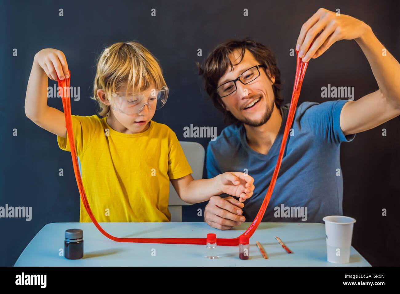 Father and son conduct chemical experiments at home. Home made slime ...