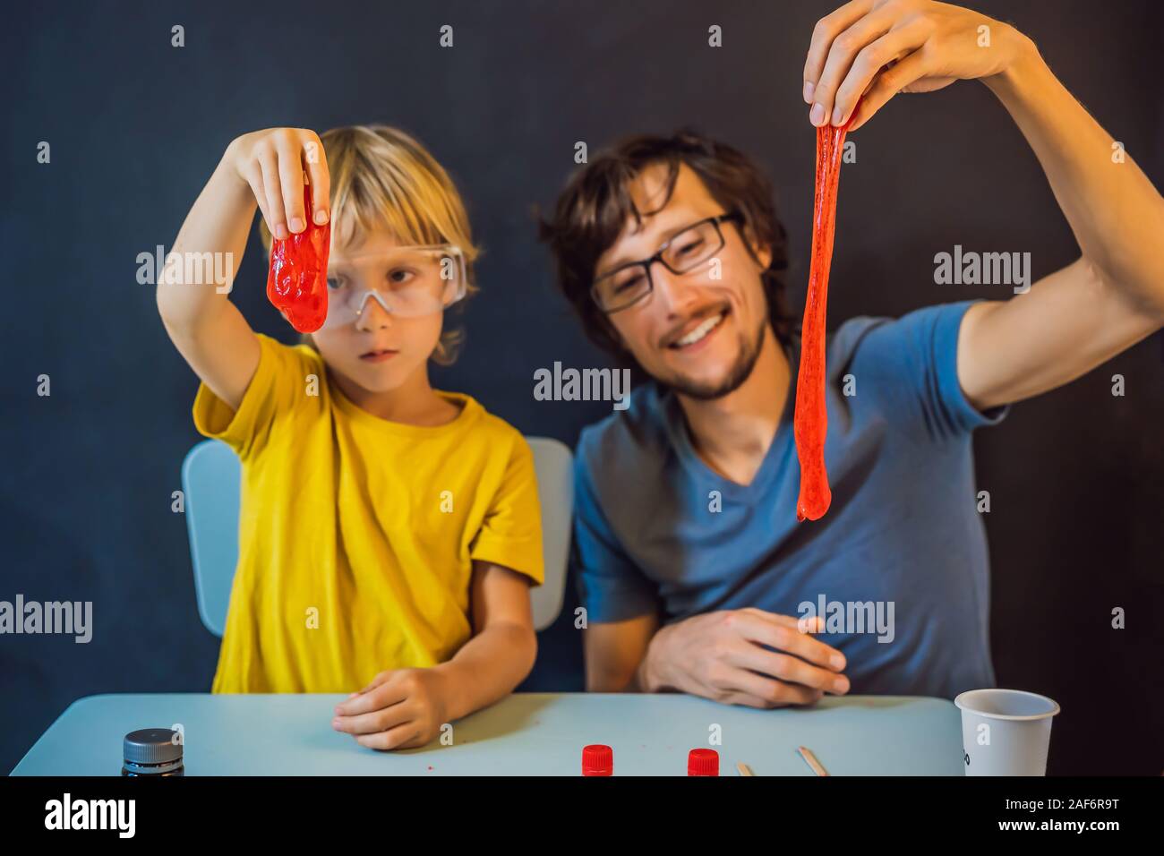 Father and son conduct chemical experiments at home. Home made slime ...