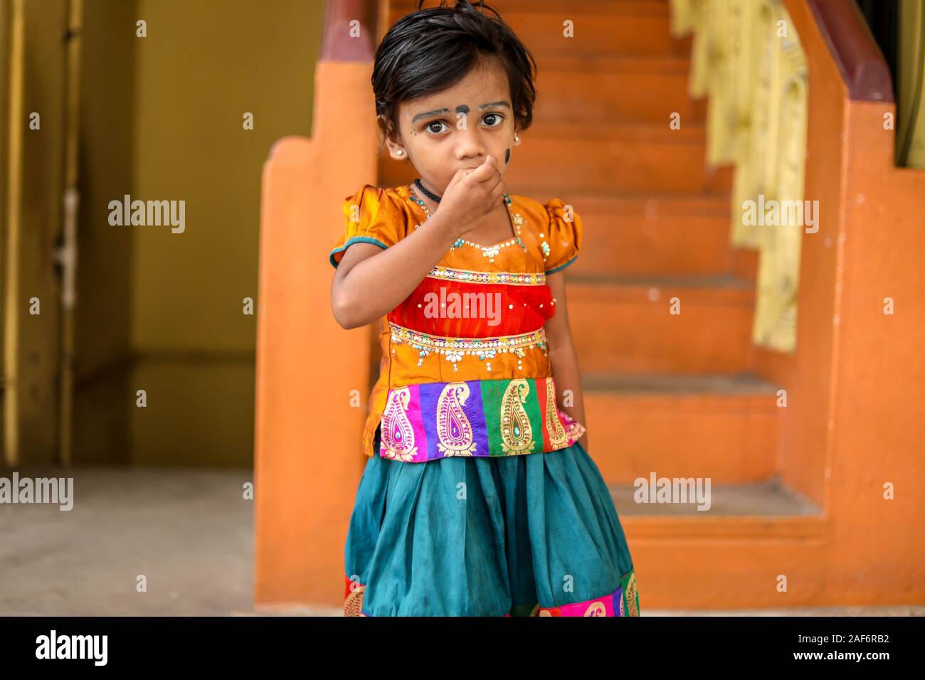 Happy child little girl standing at home against stair Stock Photo - Alamy