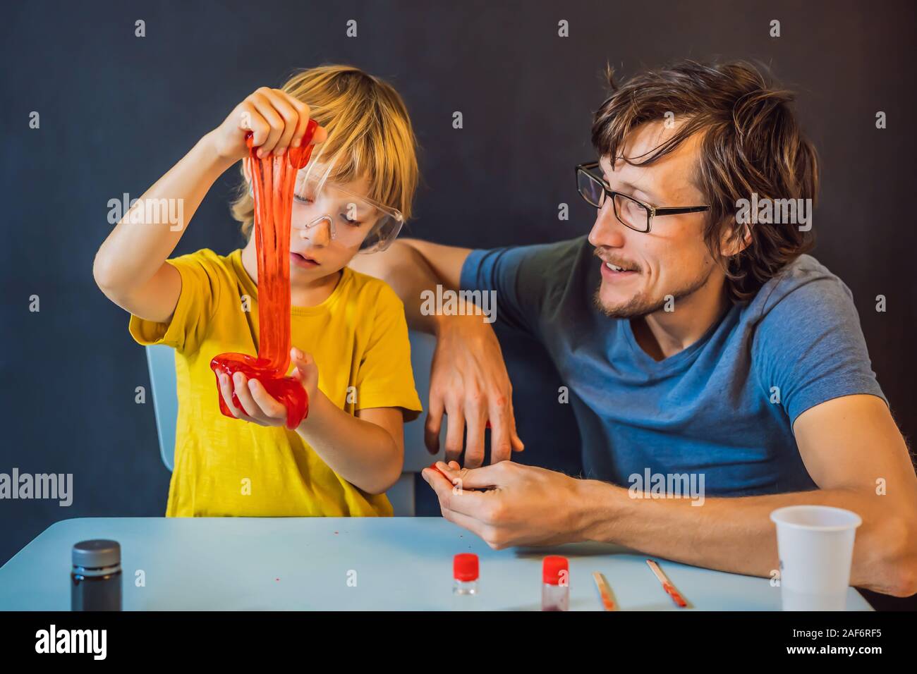 Father and son conduct chemical experiments at home. Home made slime ...