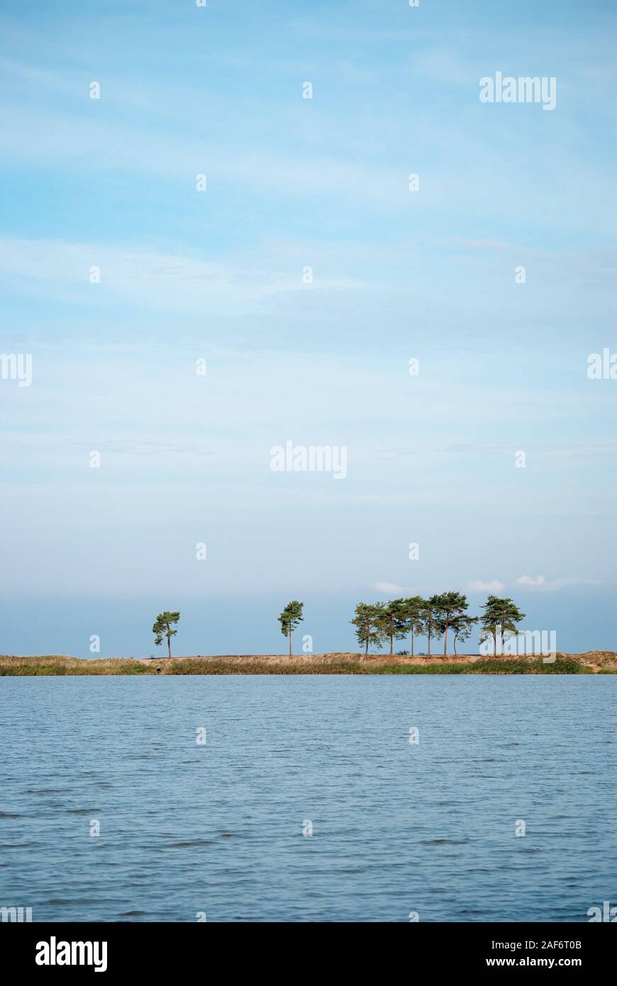 Blue sky and water of the lake and the sandy spit with the line of ...