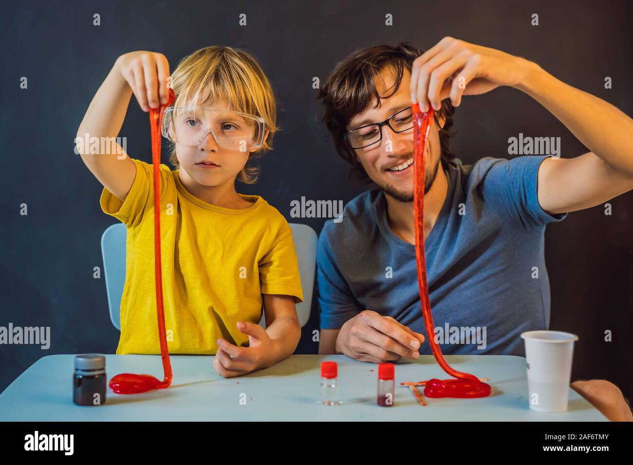Father and son conduct chemical experiments at home. Home made slime ...