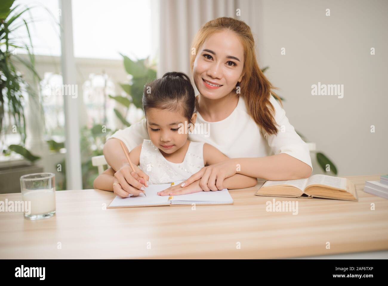 Mother teaching daughter how to write Stock Photo - Alamy