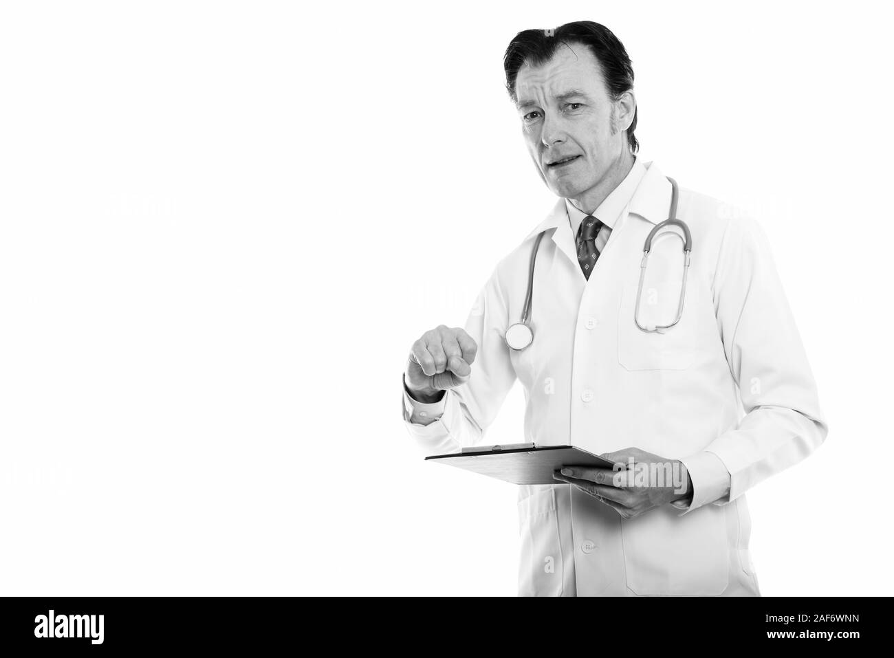 Studio shot of mature angry man doctor holding clipboard with fist ...